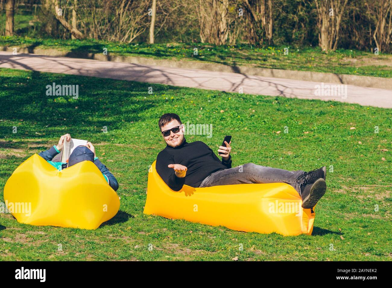 two men friends laying on yellow inflatable mattress reading books ...