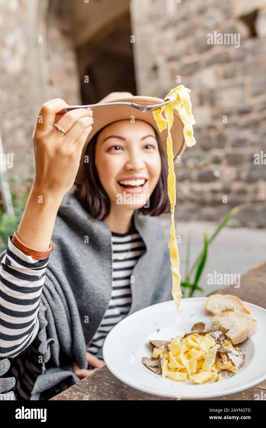Happy asian woman eating pasta with truffle in outdoor italian ...