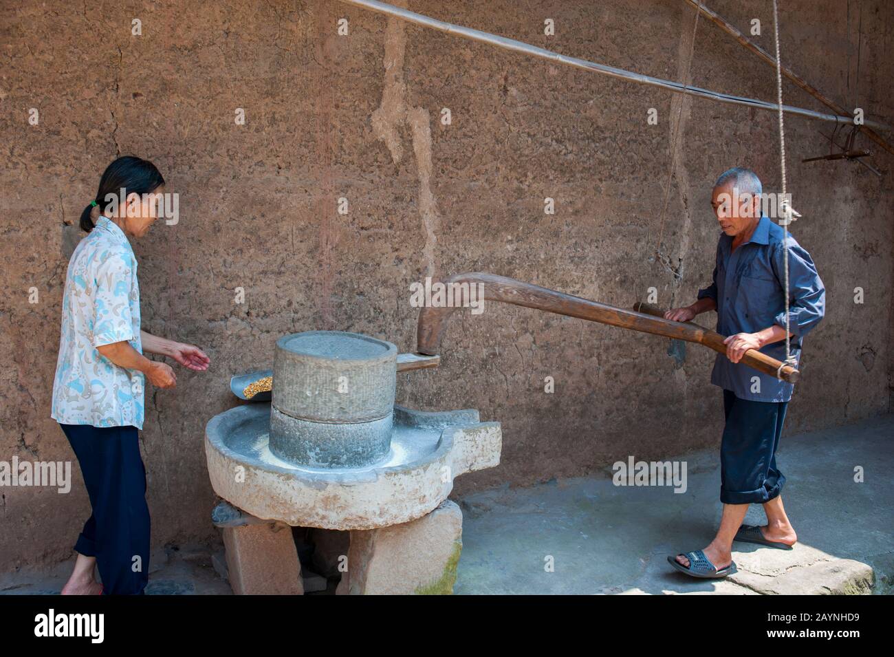 Farmers grinding corn with a millstone in the courtyard of an old ...