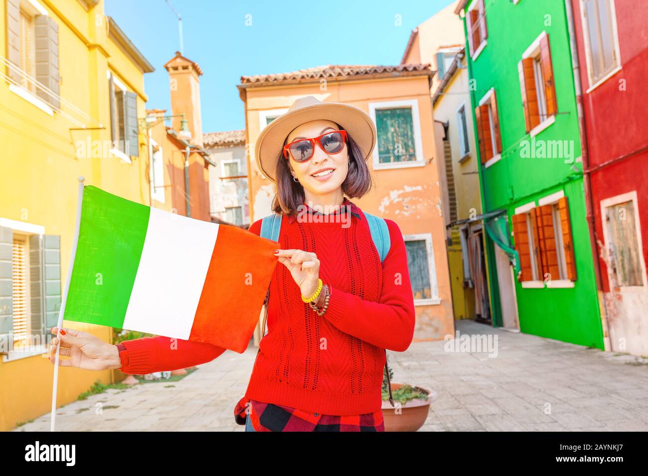 Young happy traveler with italian flag near famous colorful buildings ...