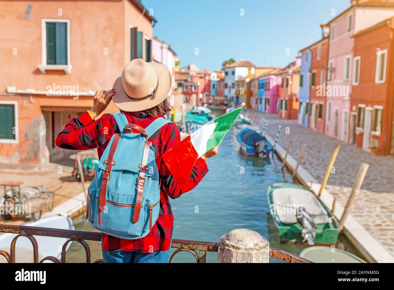 Young happy traveler with italian flag near famous colorful buildings ...