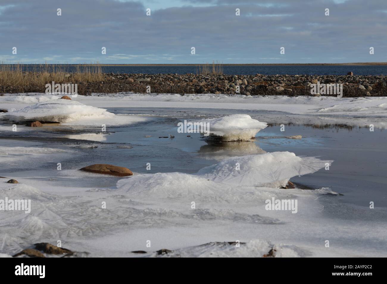 Ice on a rock sheared from the lake due to wind action with blue sky in ...