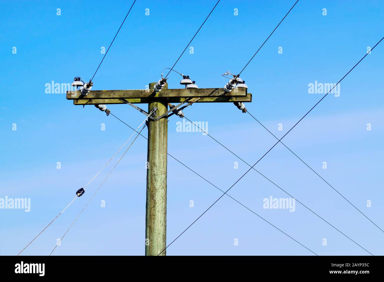 A wooden utility pole with cables against a blue sky Stock Photo - Alamy