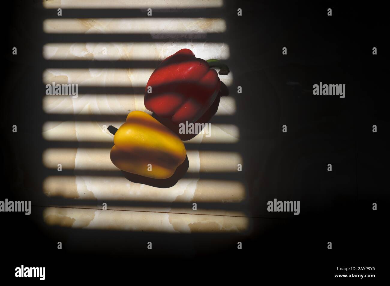 Yellow and Red Paprika with with striped shadow lines from a window to ...
