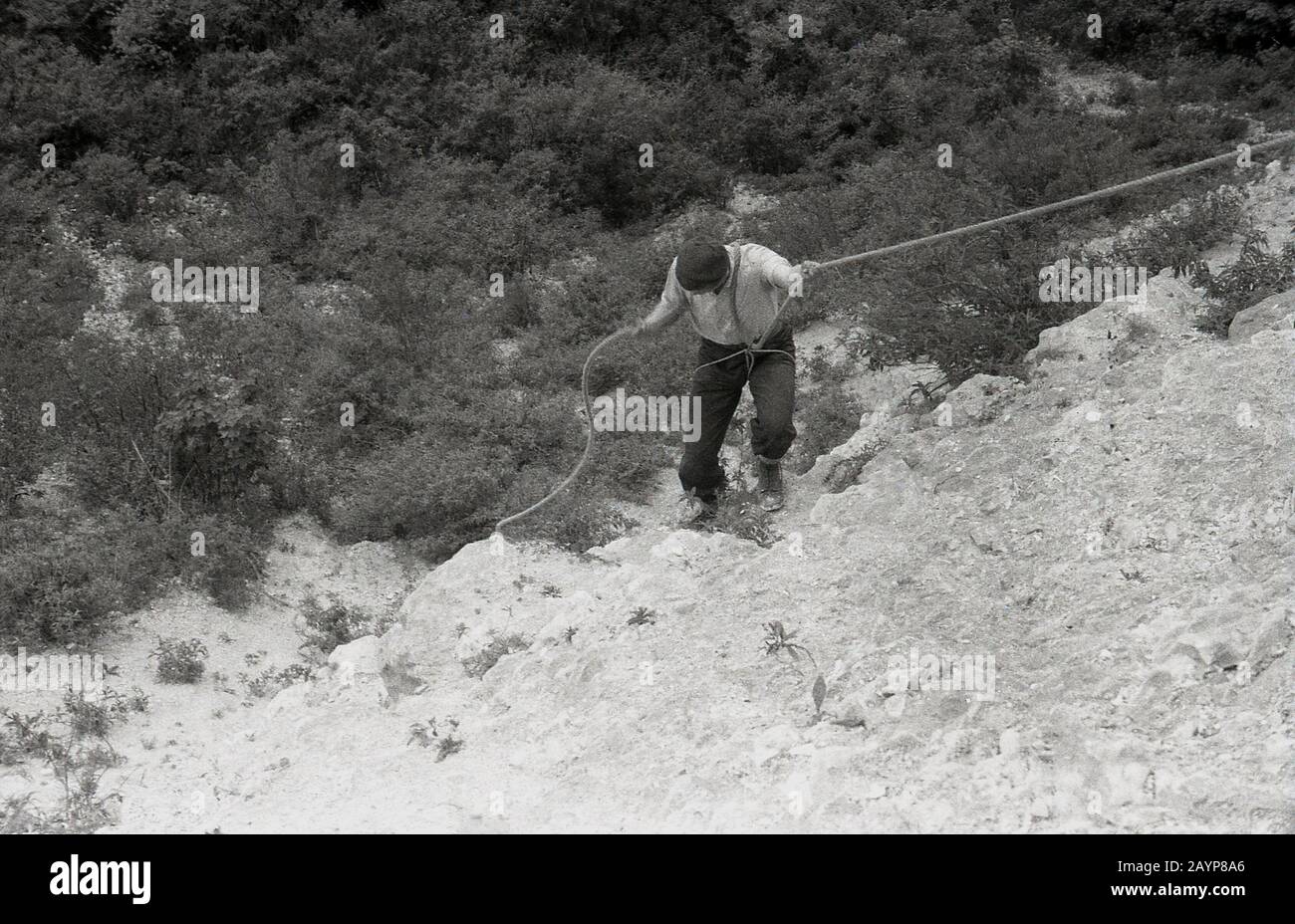 1950s, historical, holding onto a rope, a young man abseiling or ...
