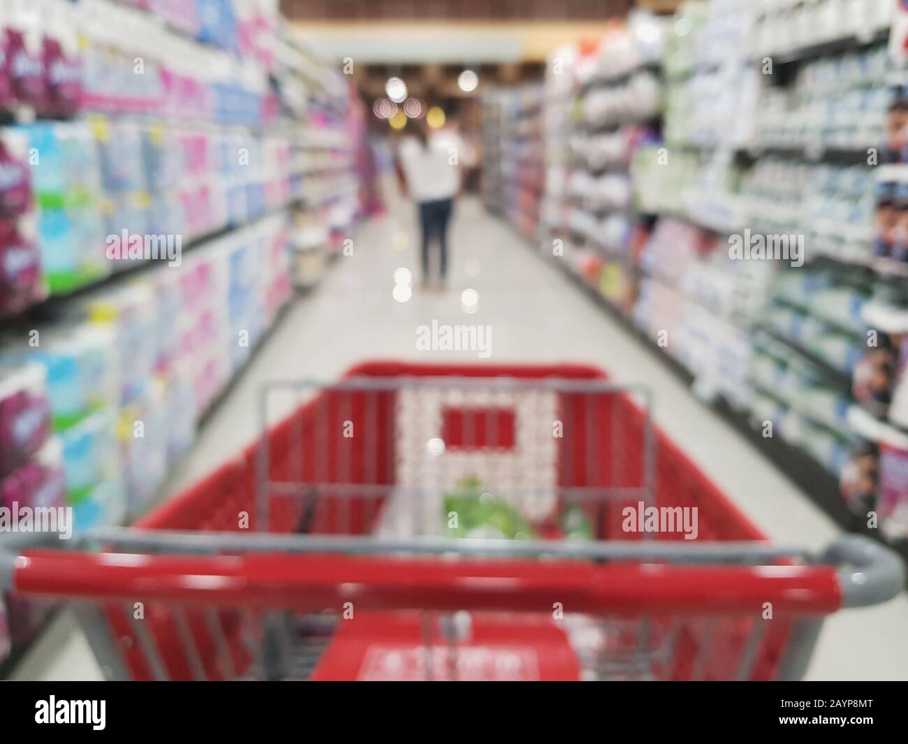Blurred supermarket background with cart and customer Stock Photo - Alamy