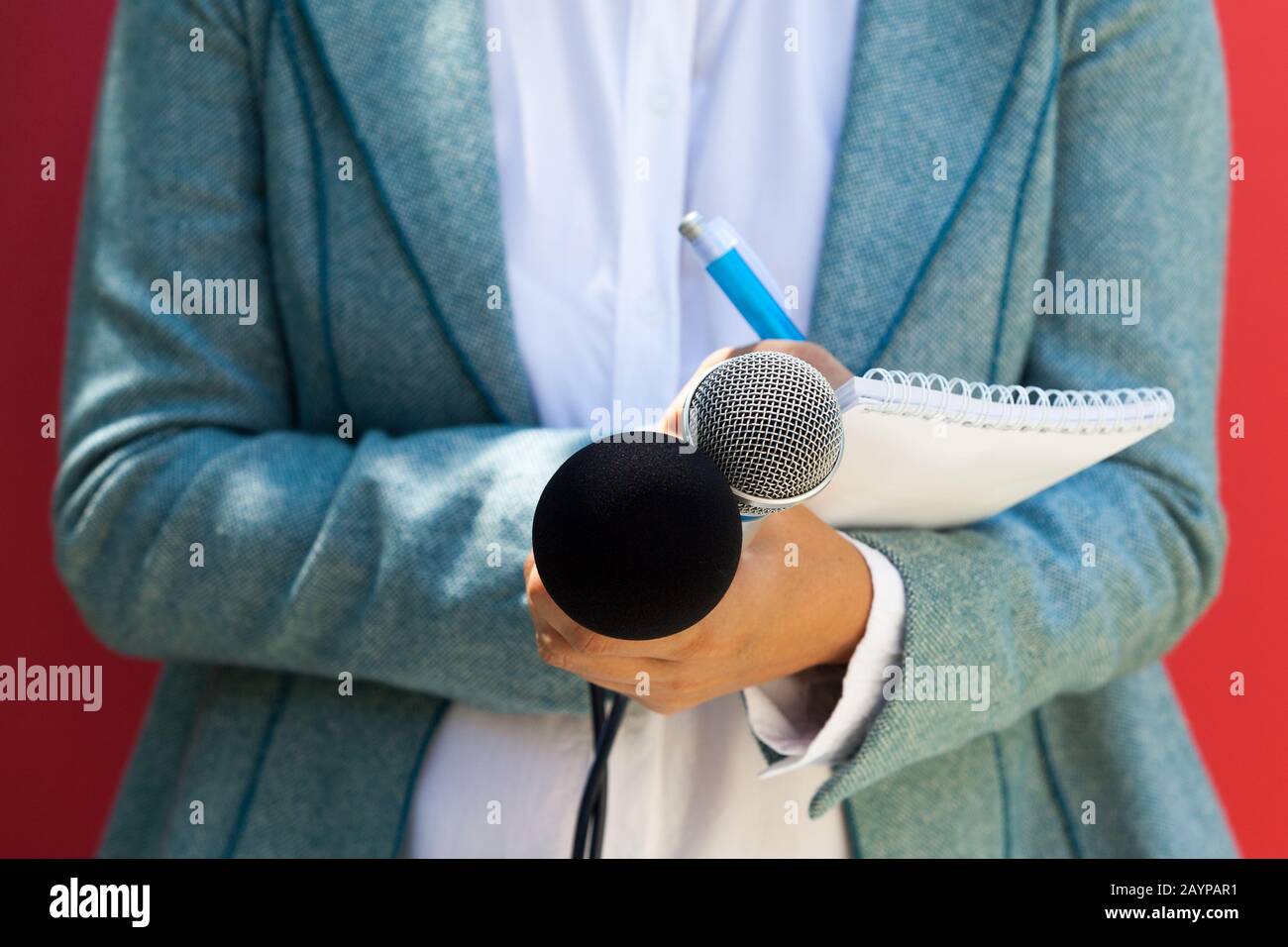 Female reporter at press conference, writing notes, holding microphone ...