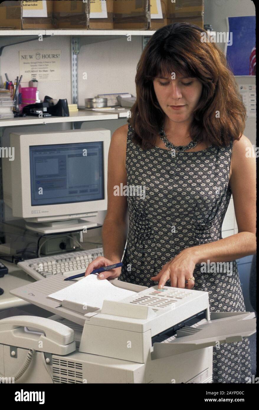 Austin, Texas USA: Female Hispanic office manager uses a fax machine ...