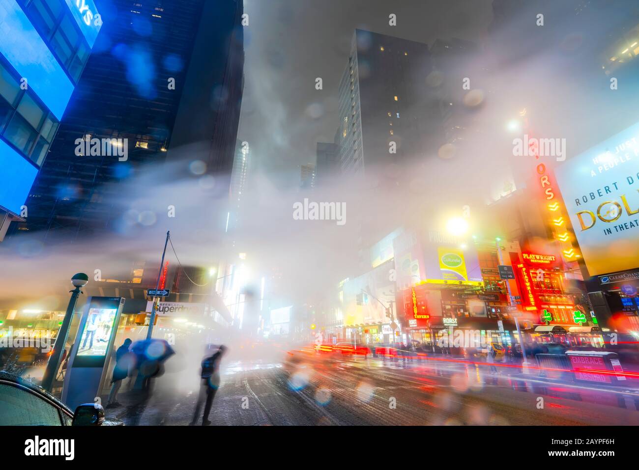 The steam rises and drifts over the Avenue in the snow night around the ...