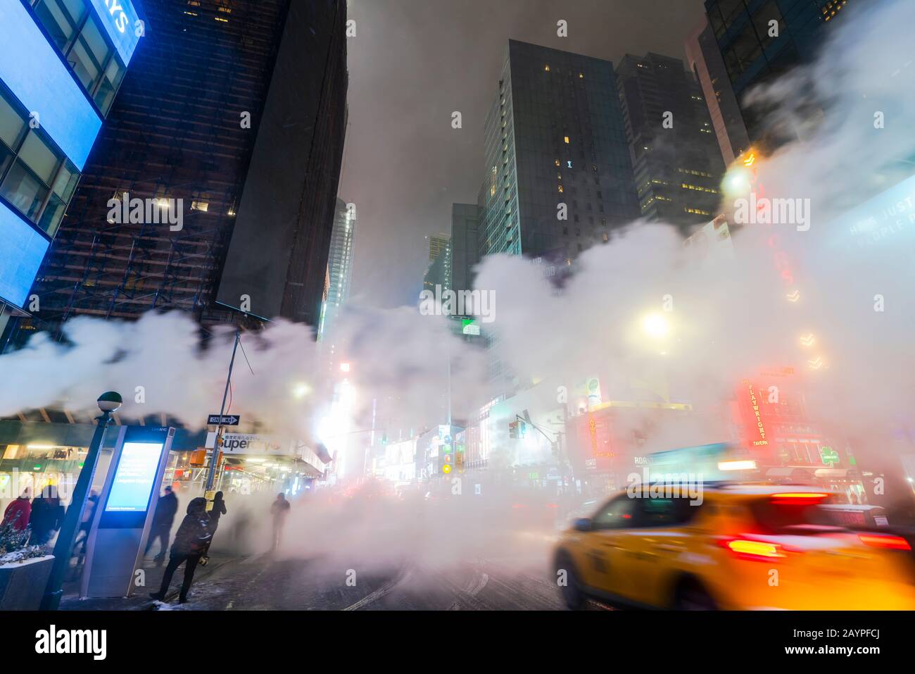 The steam rises and drifts over the Avenue in the snow night around the ...