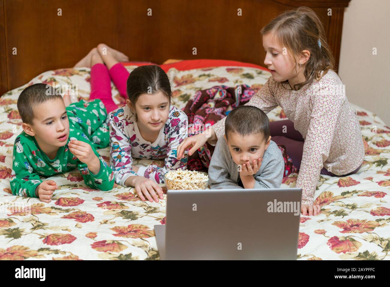 Pretty children looking at computer monitor while laying in bed and ...