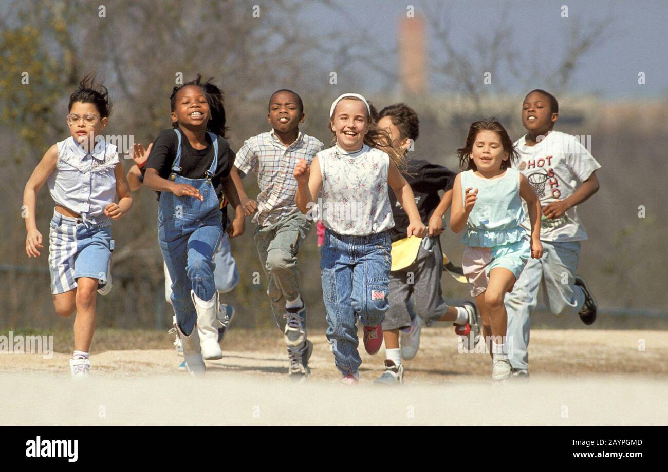 Multi-racial group of elementary school students run on playground ...