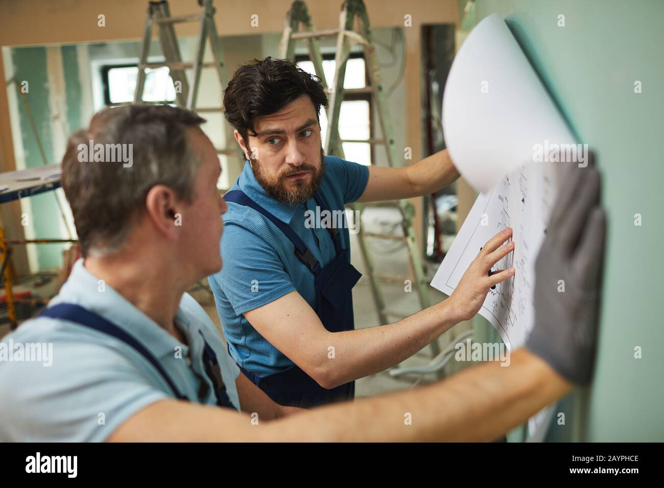 Side view portrait of father and son looking at floor plans while ...