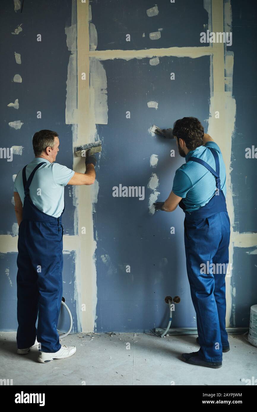 Full length back view portrait of two construction workers building dry ...