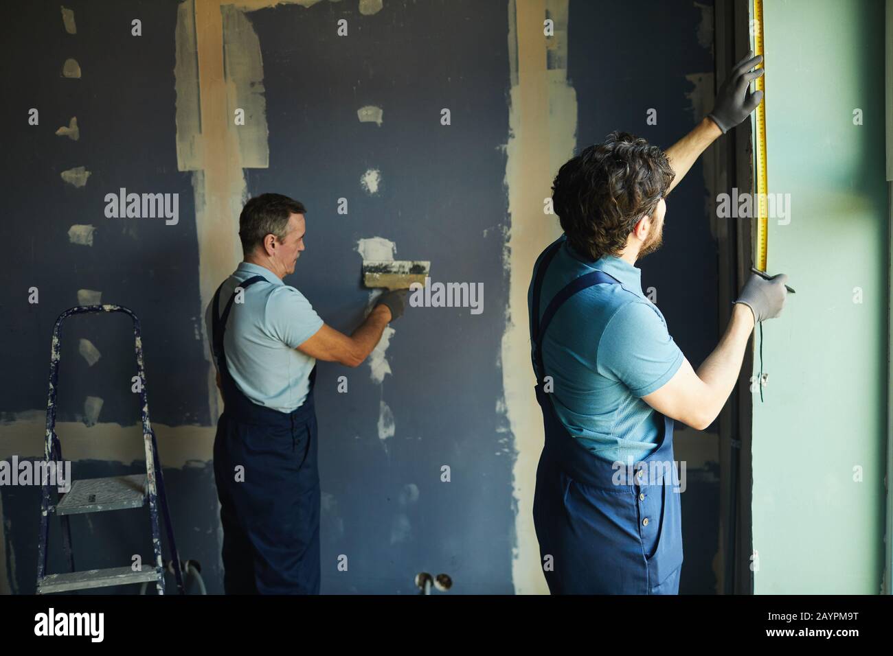 Back view of construction crew working in room while building or renovating house, copy space ...