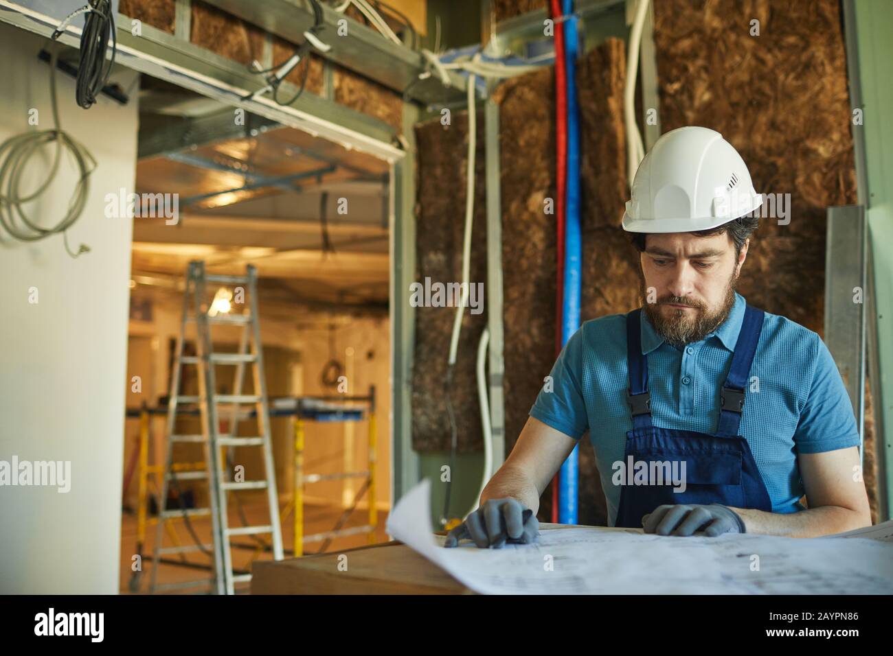 Waist up portrait of bearded construction worker wearing hardhat and ...