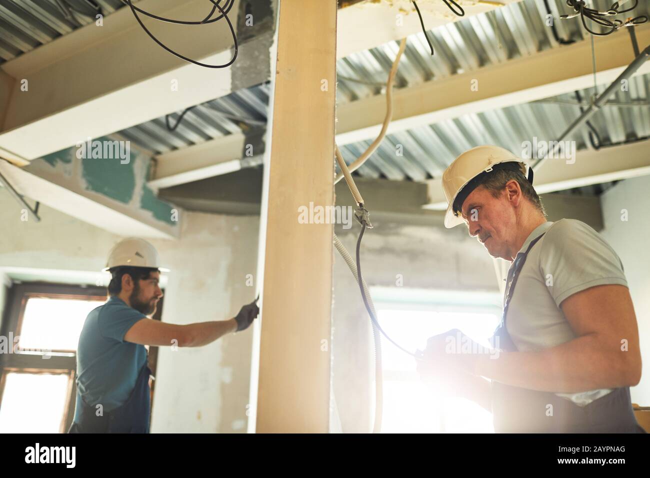 Side view at two construction crew workers separated by wall while ...
