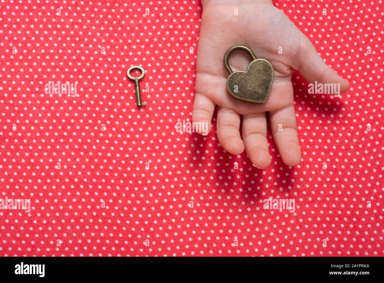 Hand holding a heart shaped lock and key on a red background Stock ...