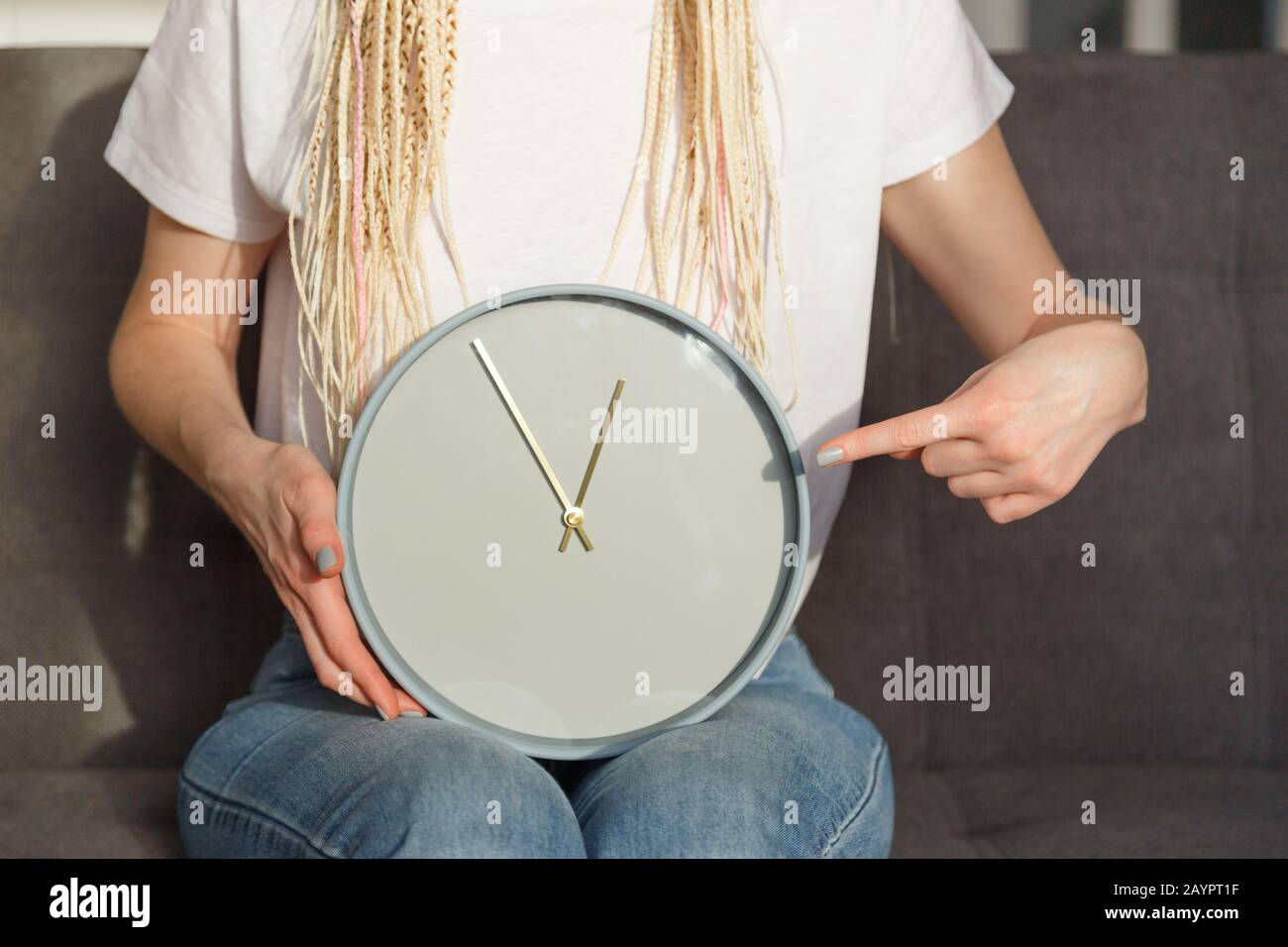 Woman point to clock in her hand. Almost one our Stock Photo - Alamy