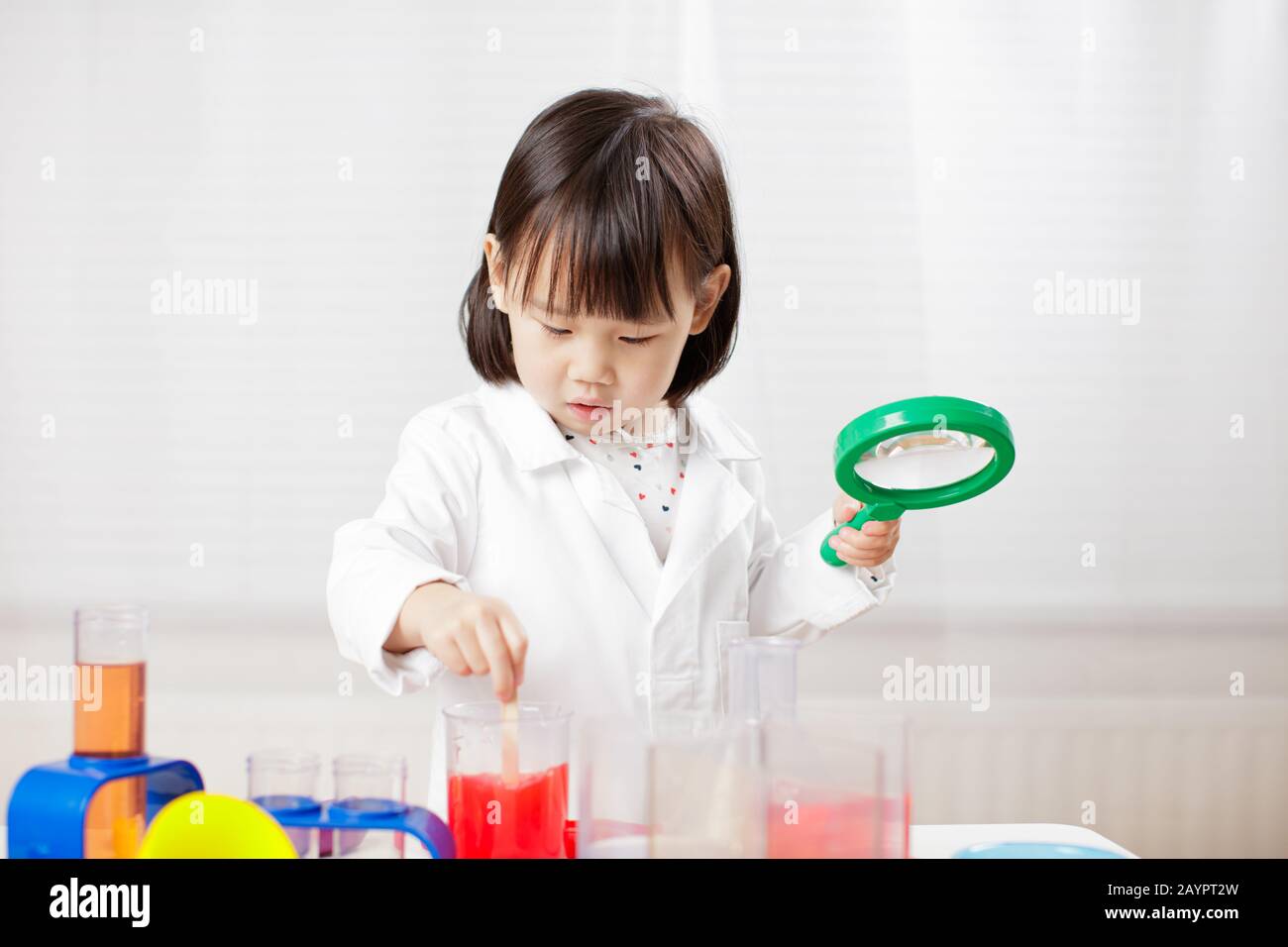 toddler girl pretend play scientist role at home against white ...