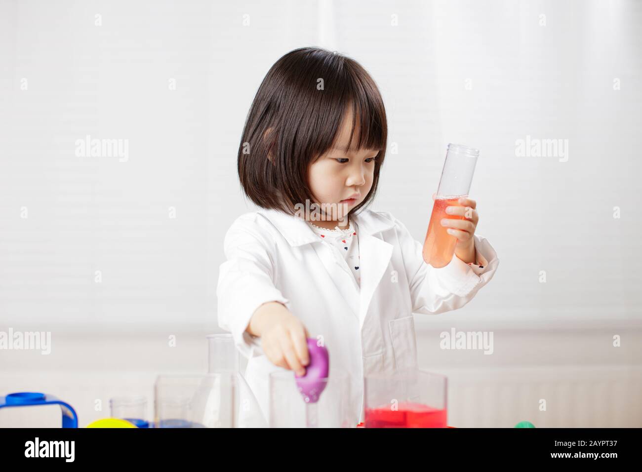 toddler girl pretend play scientist role at home against white ...