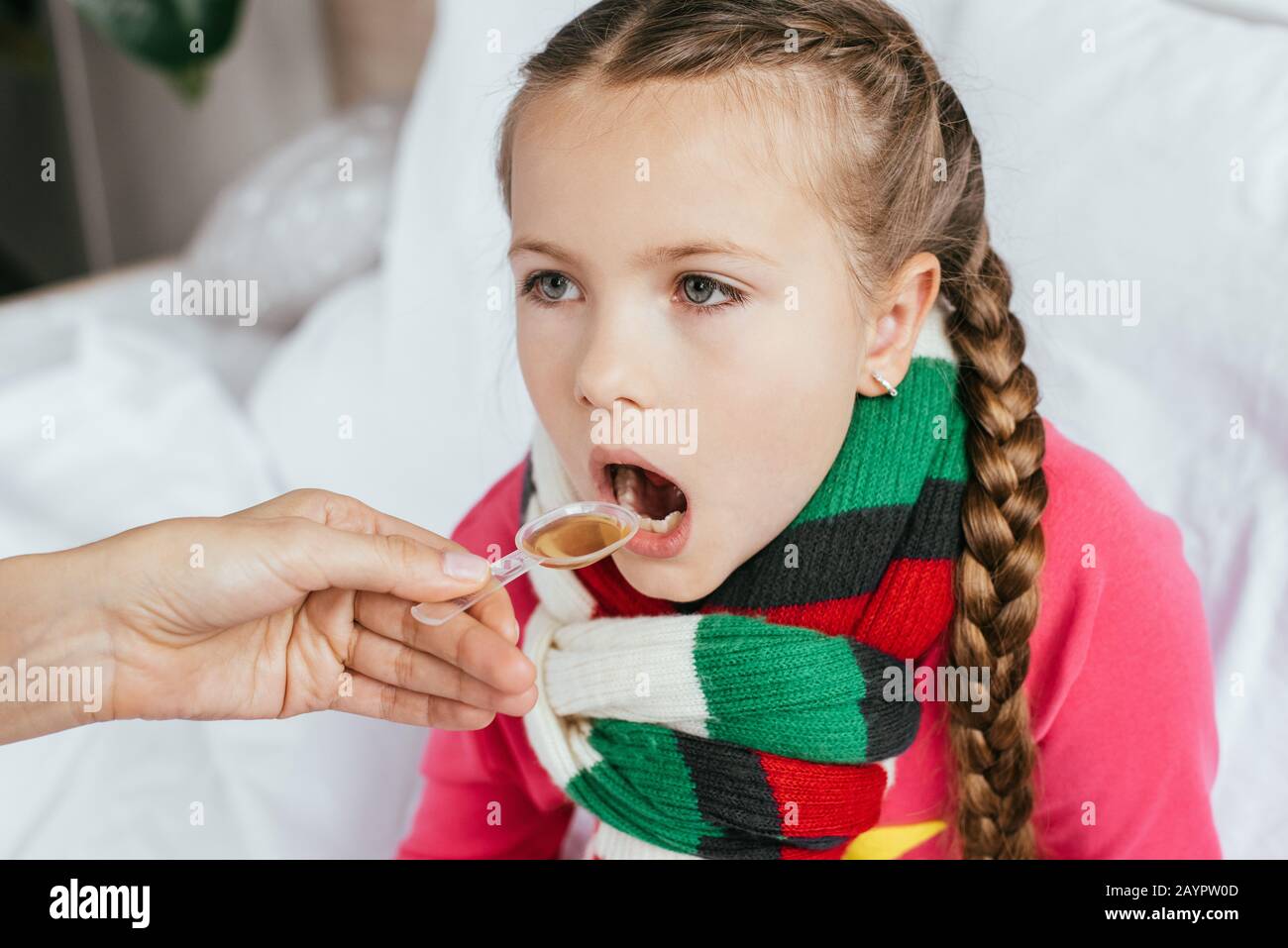 mom giving syrup to ill daughter with scarf in bed Stock Photo - Alamy
