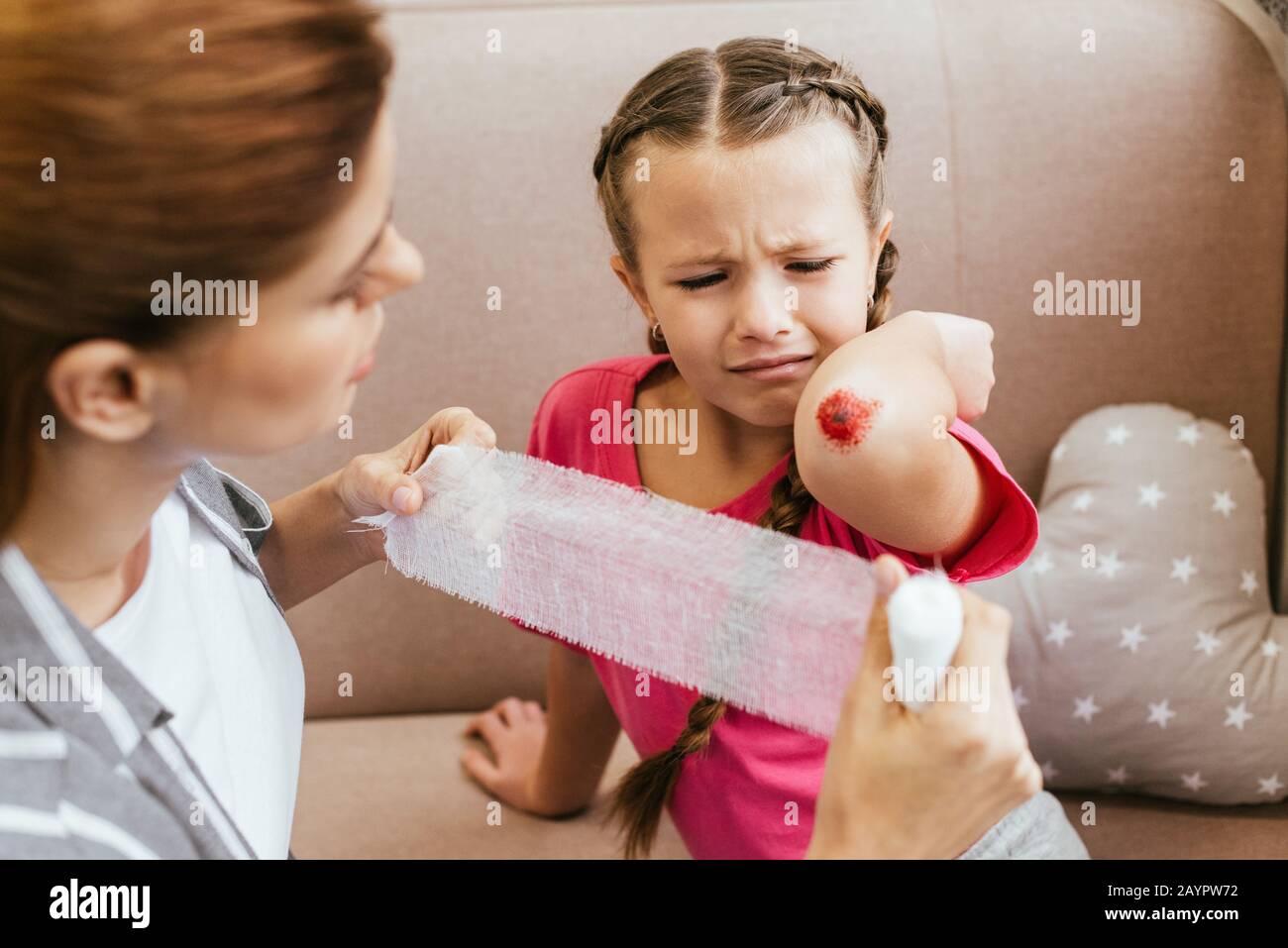 worried mother wounding bandage around elbow of crying daughter Stock ...
