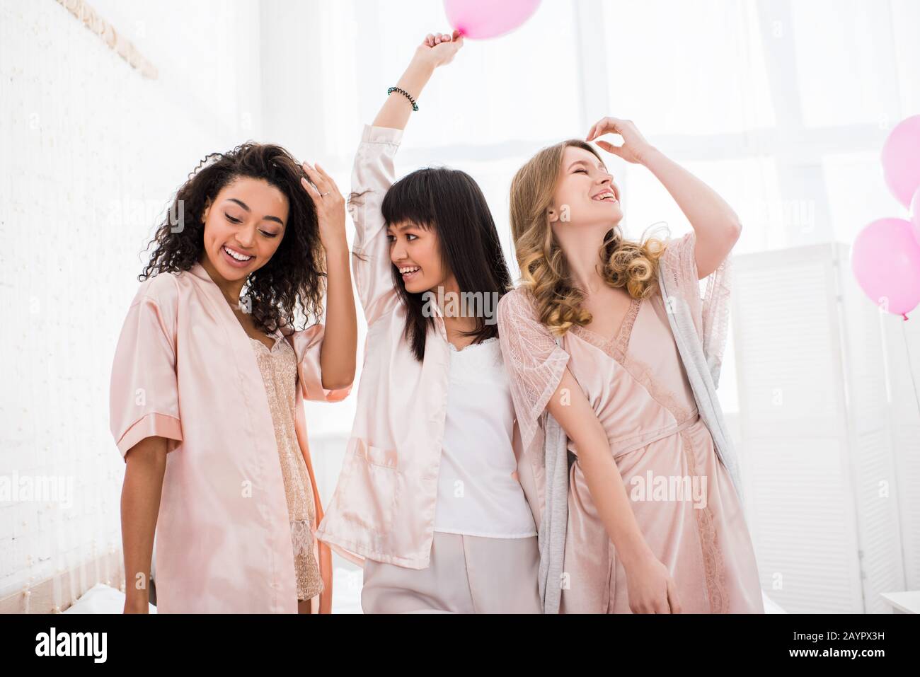 smiling multicultural girls having fun in bedroom with pink balloons ...