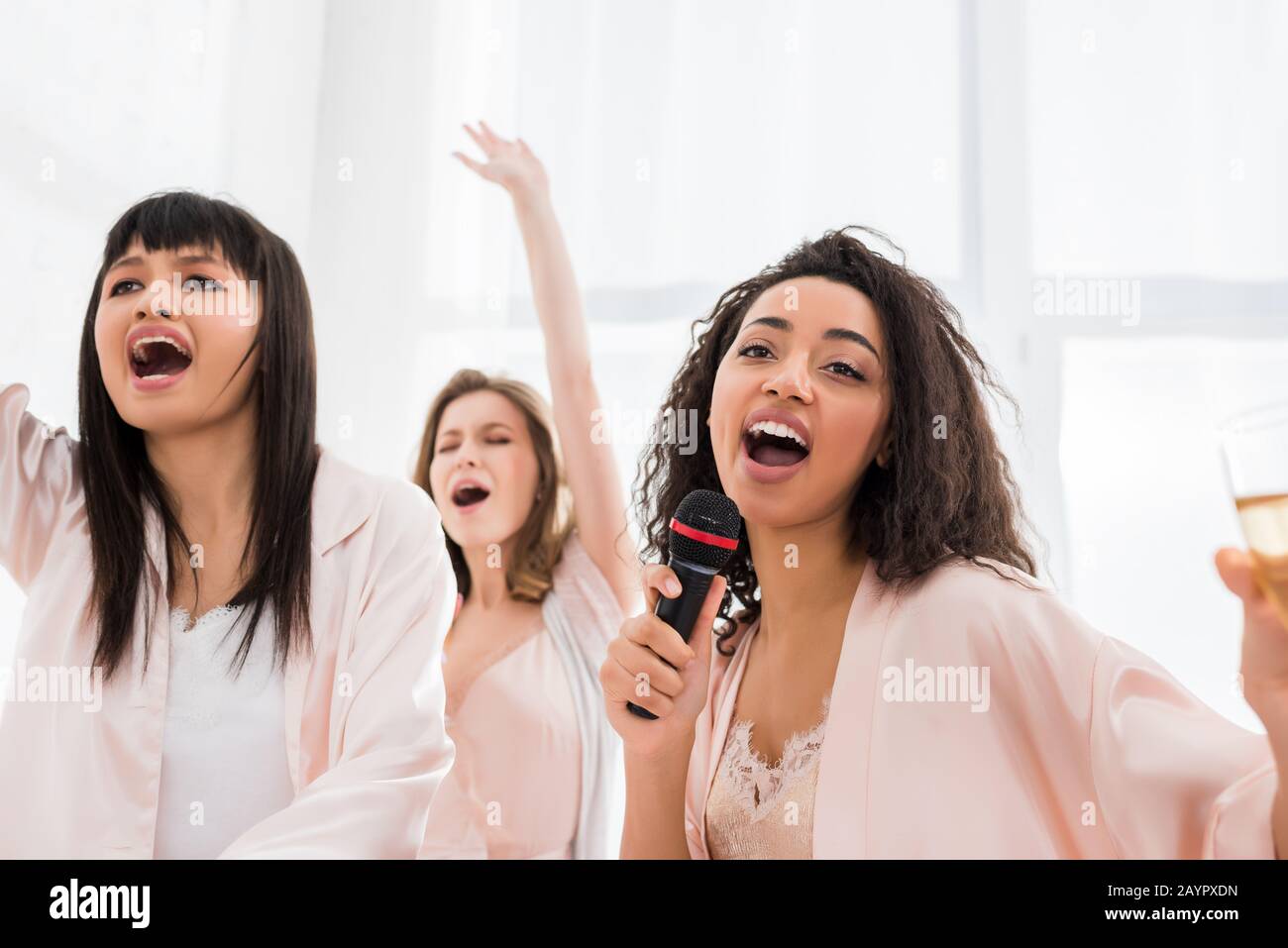 beautiful smiling multicultural girls singing with microphone on pajama ...
