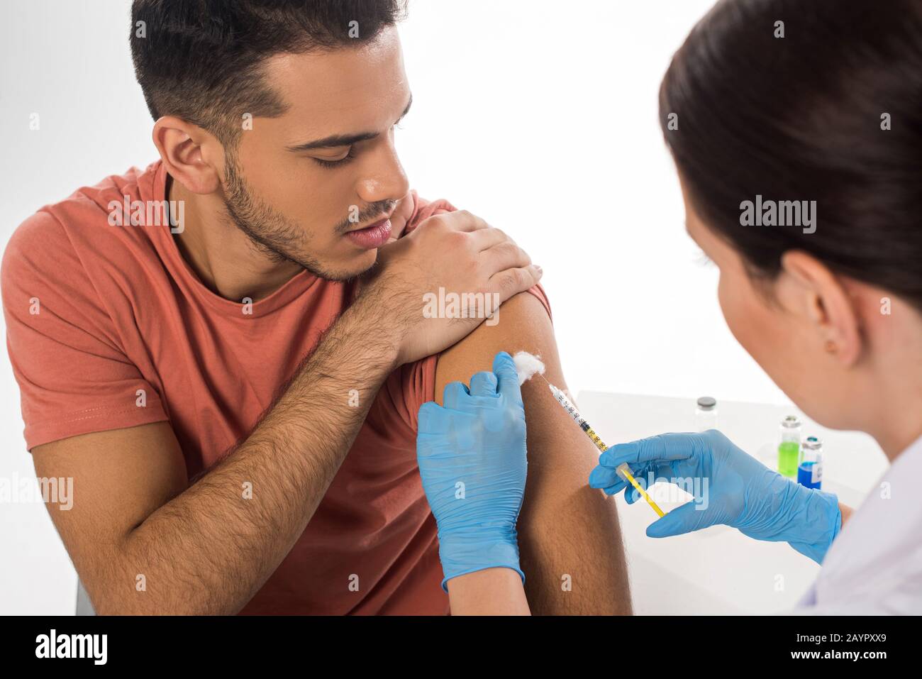 Selective focus of doctor doing injection to handsome patient isolated ...