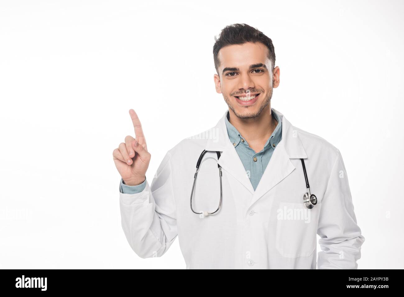 Handsome doctor pointing with finger and smiling at camera isolated on ...
