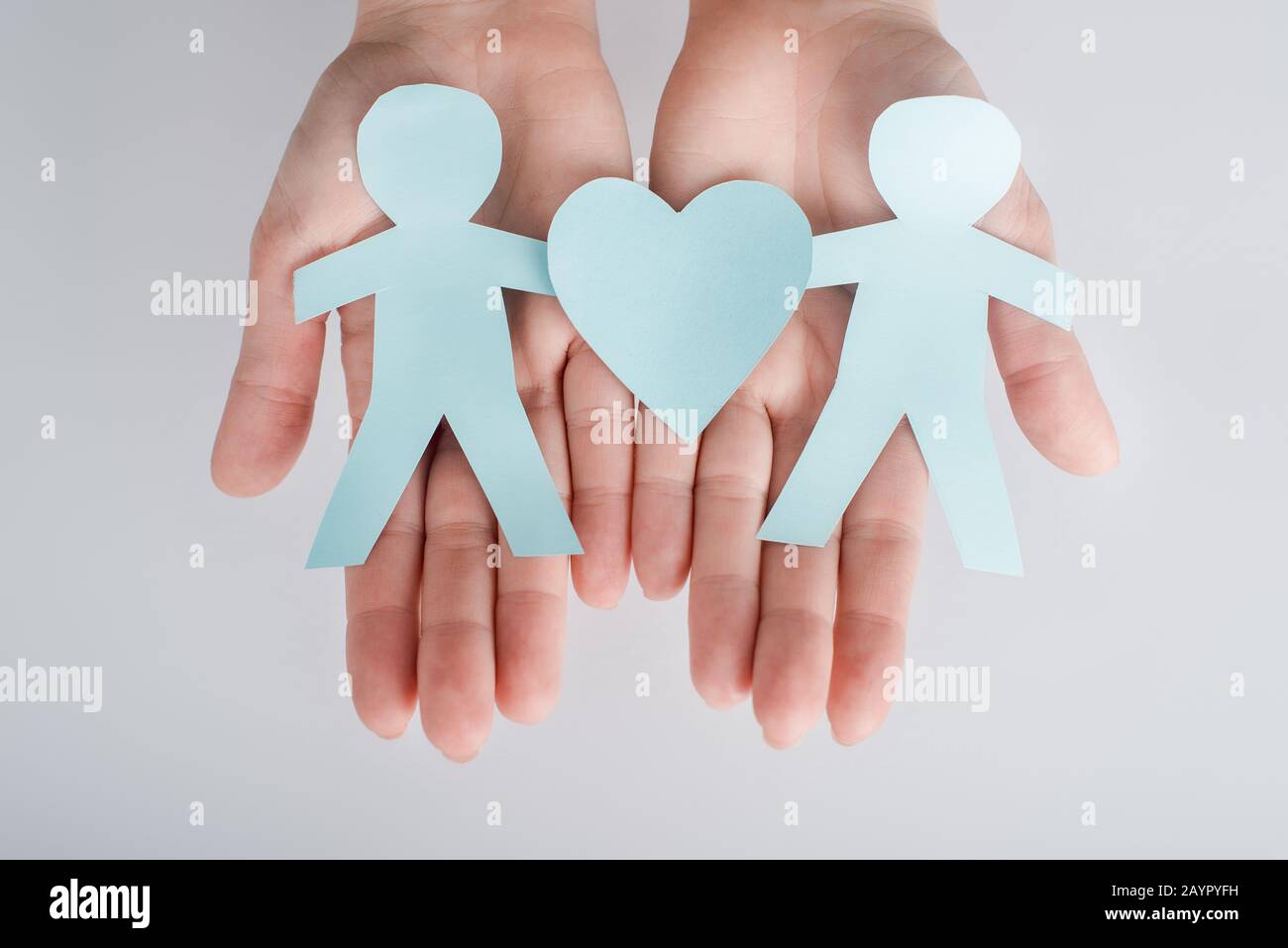 top view of woman holding figures of people cut from paper with heart ...