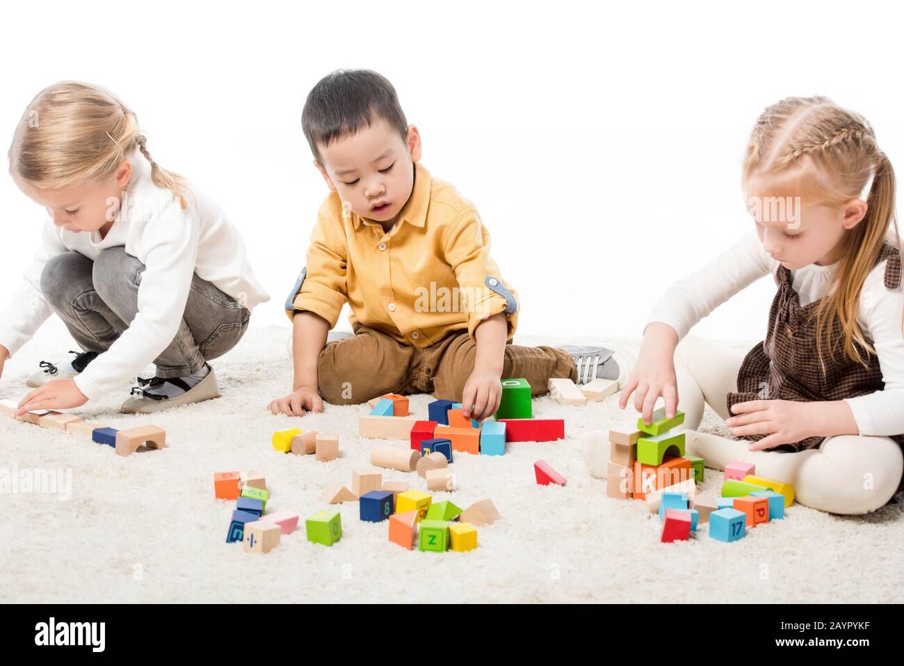 multicultural kids playing with wooden blocks on carpet, isolated on ...