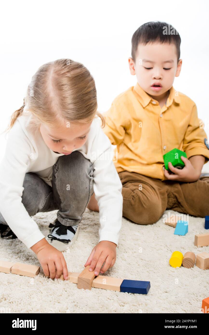 multicultural children playing with wooden blocks on carpet, isolated ...