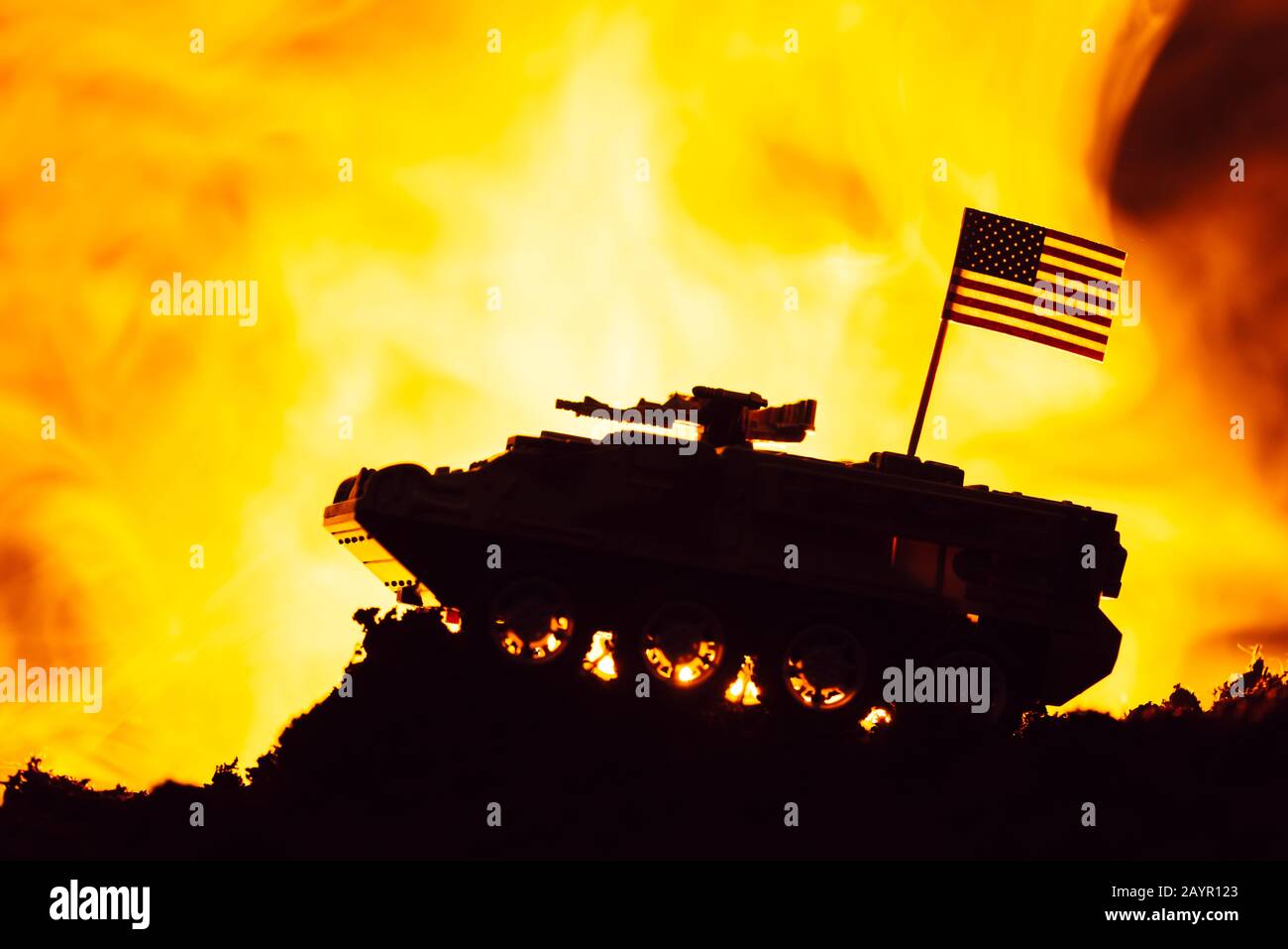Battle scene with american flag on toy tank and fire at background ...