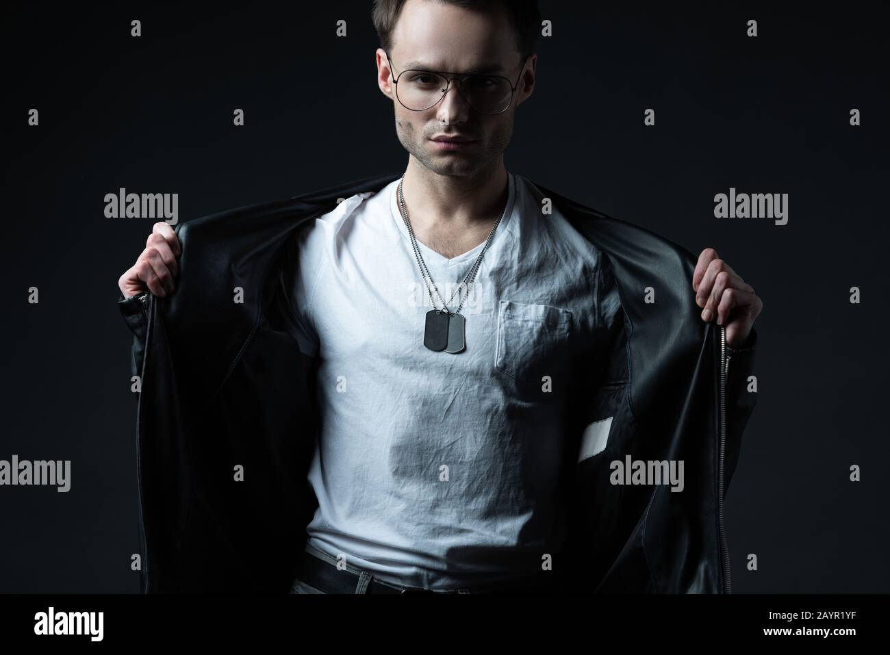 stylish brutal man taking off biker jacket isolated on black Stock ...