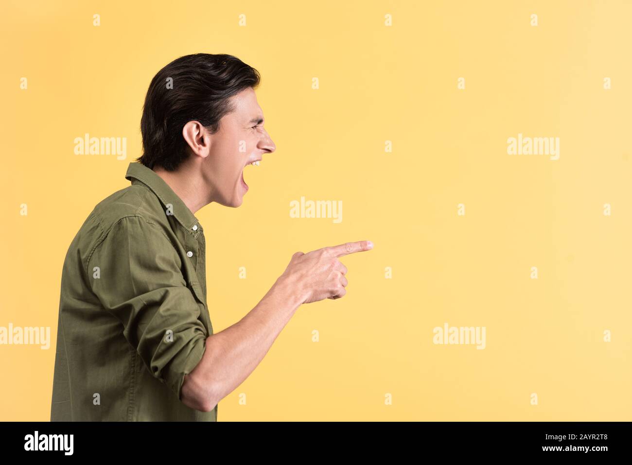 angry young man yelling and pointing isolated on yellow Stock Photo - Alamy
