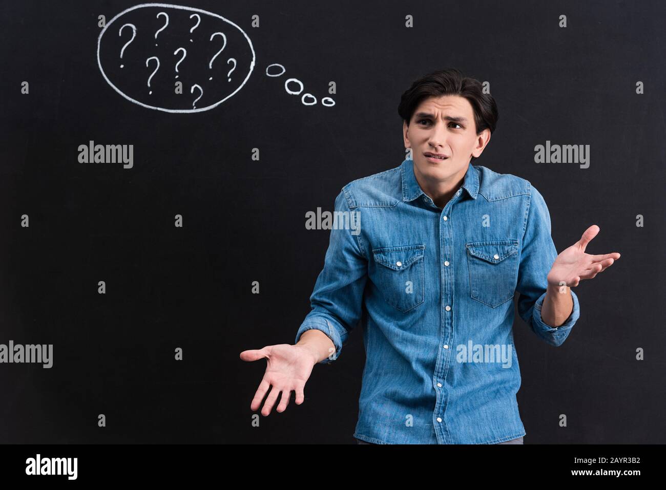 stressed young man with question marks in thought bubble on blackboard ...