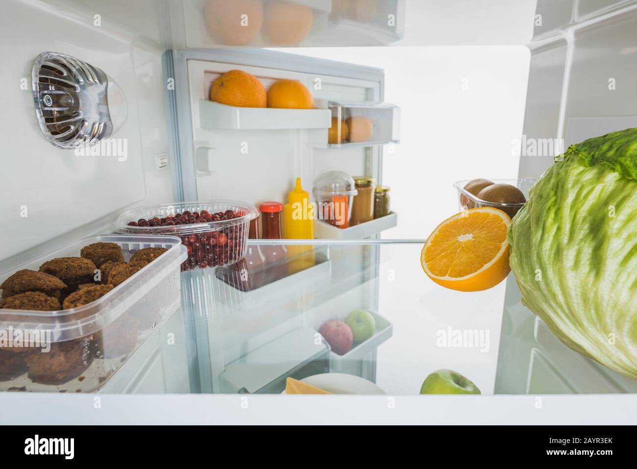 Fresh fruits, cutlets and cabbage in refrigerator with open door ...