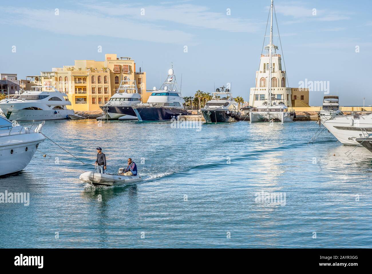 motor boat with to men sailing among luxury yachts in the New Marina ...