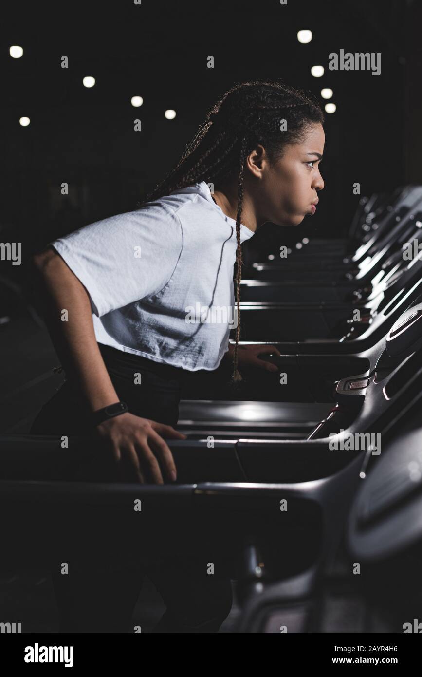 Side view of african american woman puffing out cheeks while running on ...
