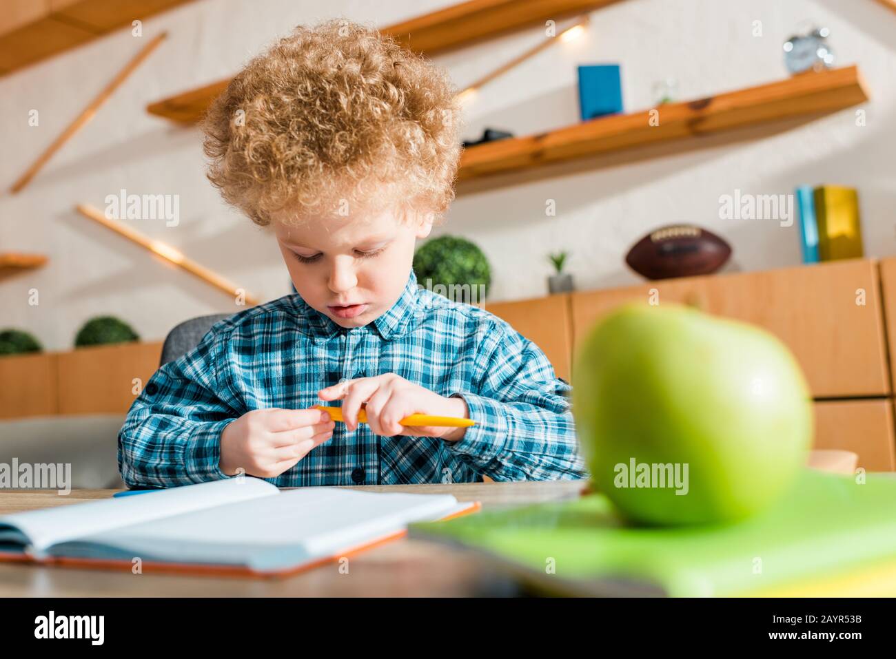 selective focus of cute and smart kid holding pen near green apple ...