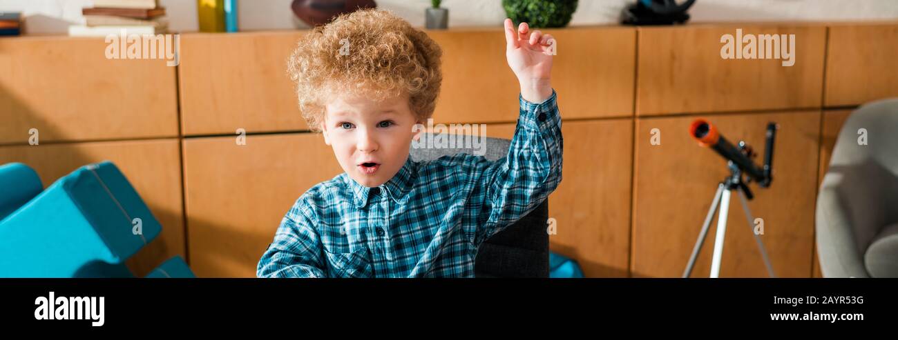 panoramic shot of emotional smart kid with raised hand at home Stock ...