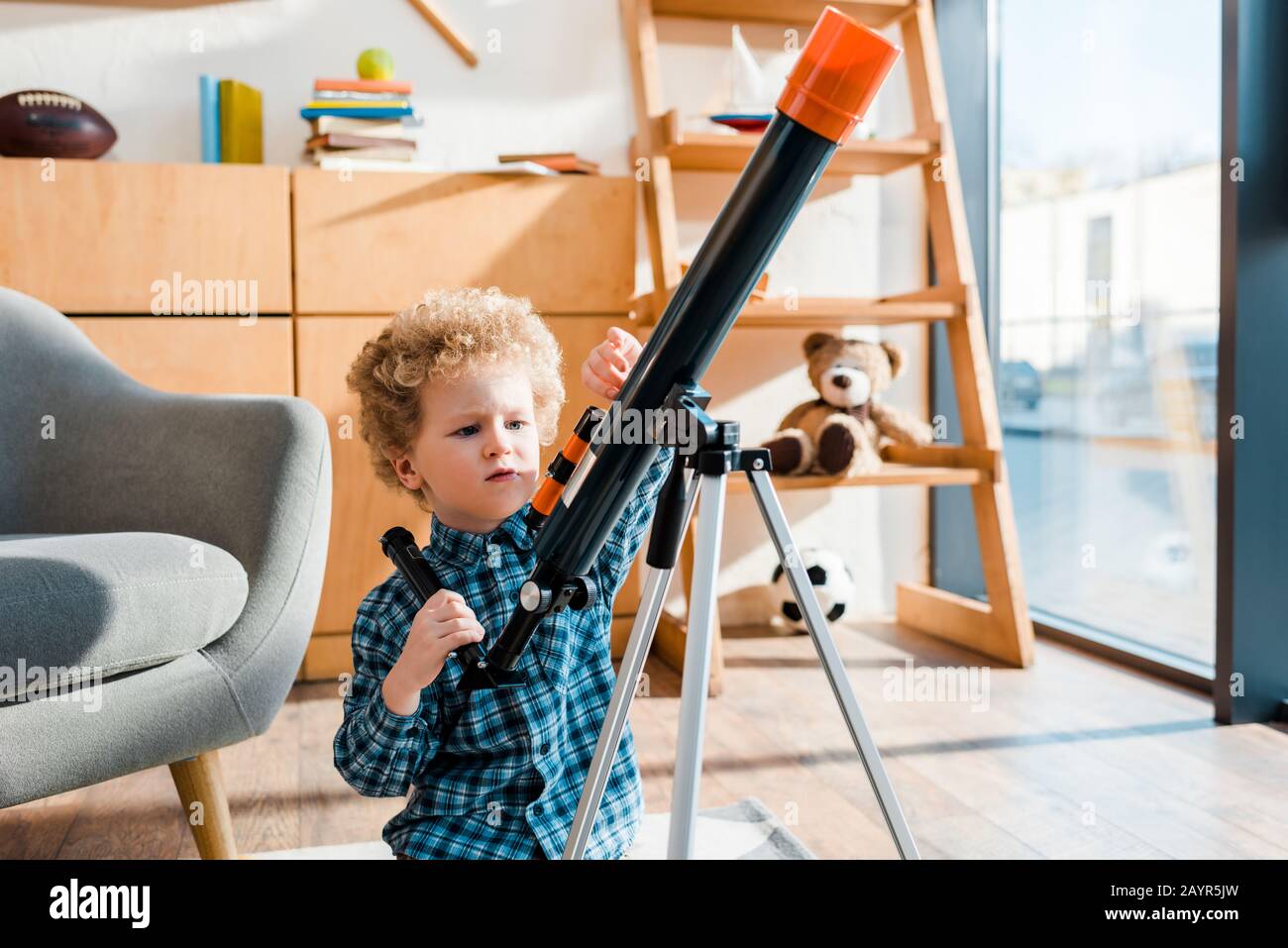 smart child touching telescope near armchair at home Stock Photo - Alamy