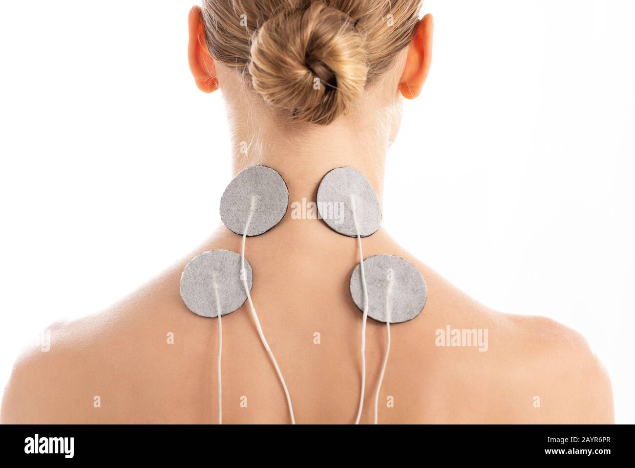 Back view of young woman with electro stimulation electrodes on neck ...
