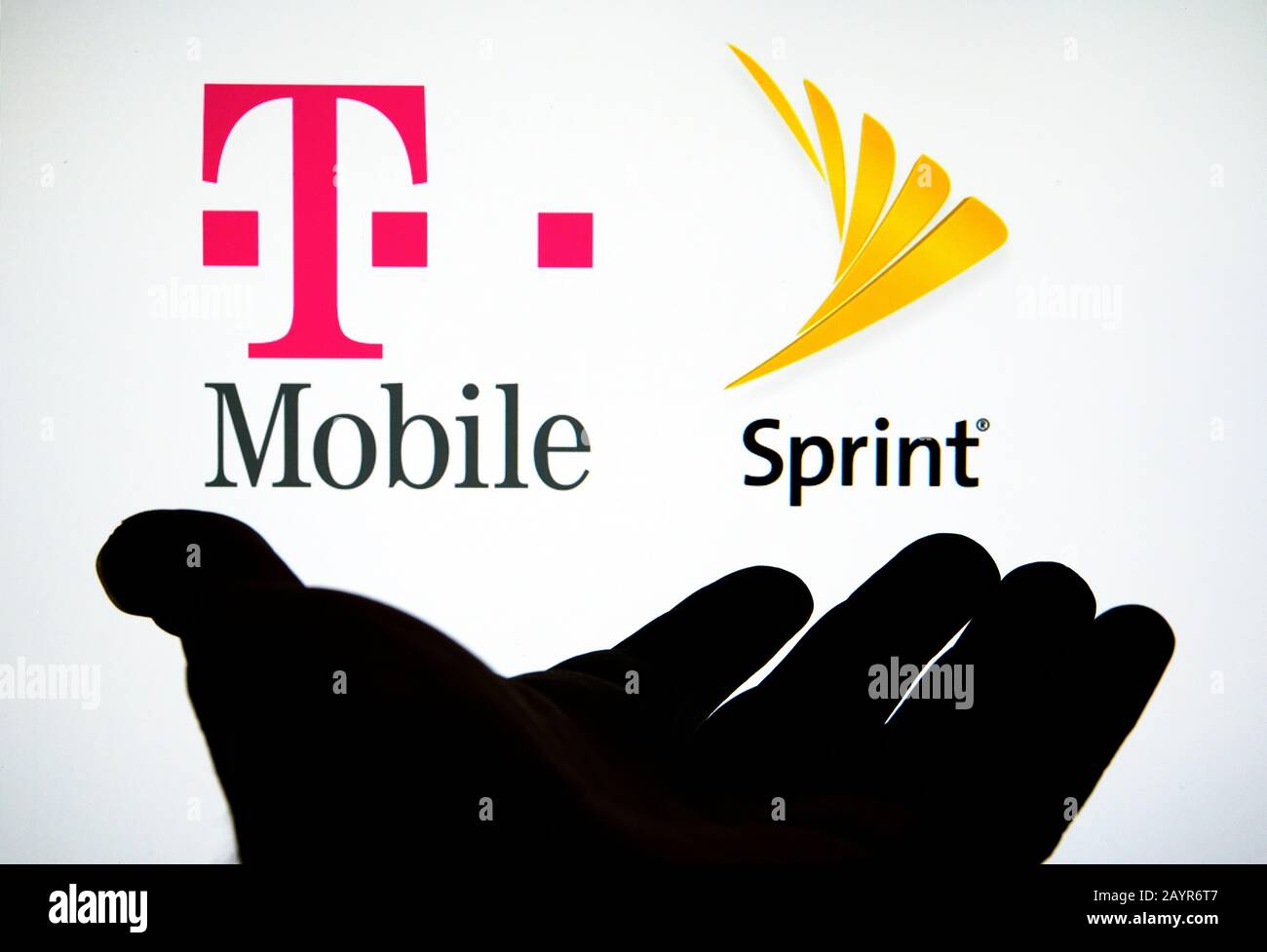 Silhouette of hand and Sprint and T mobile logos on the blurred screen ...