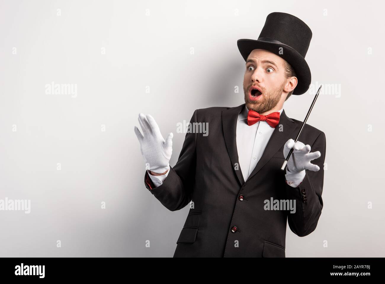 shocked magician with open mouth holding wand, isolated on grey Stock ...