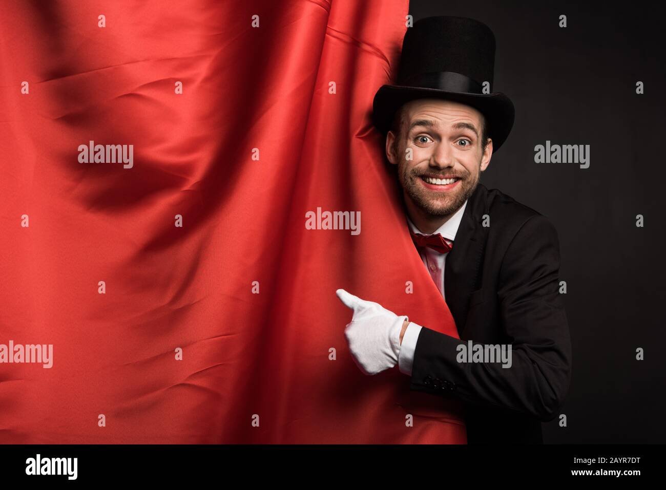 smiling magician in suit and hat showing thumb up in circus with red ...