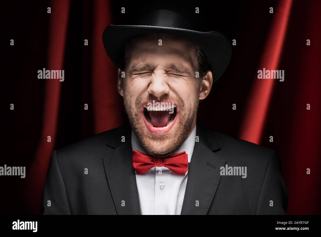 scary emotional magician with closed eyes and open mouth in circus with ...