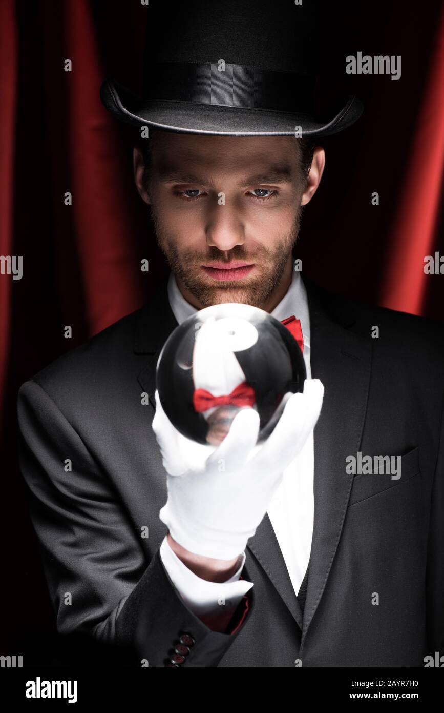 young magician holding magic ball in circus with red curtains Stock ...